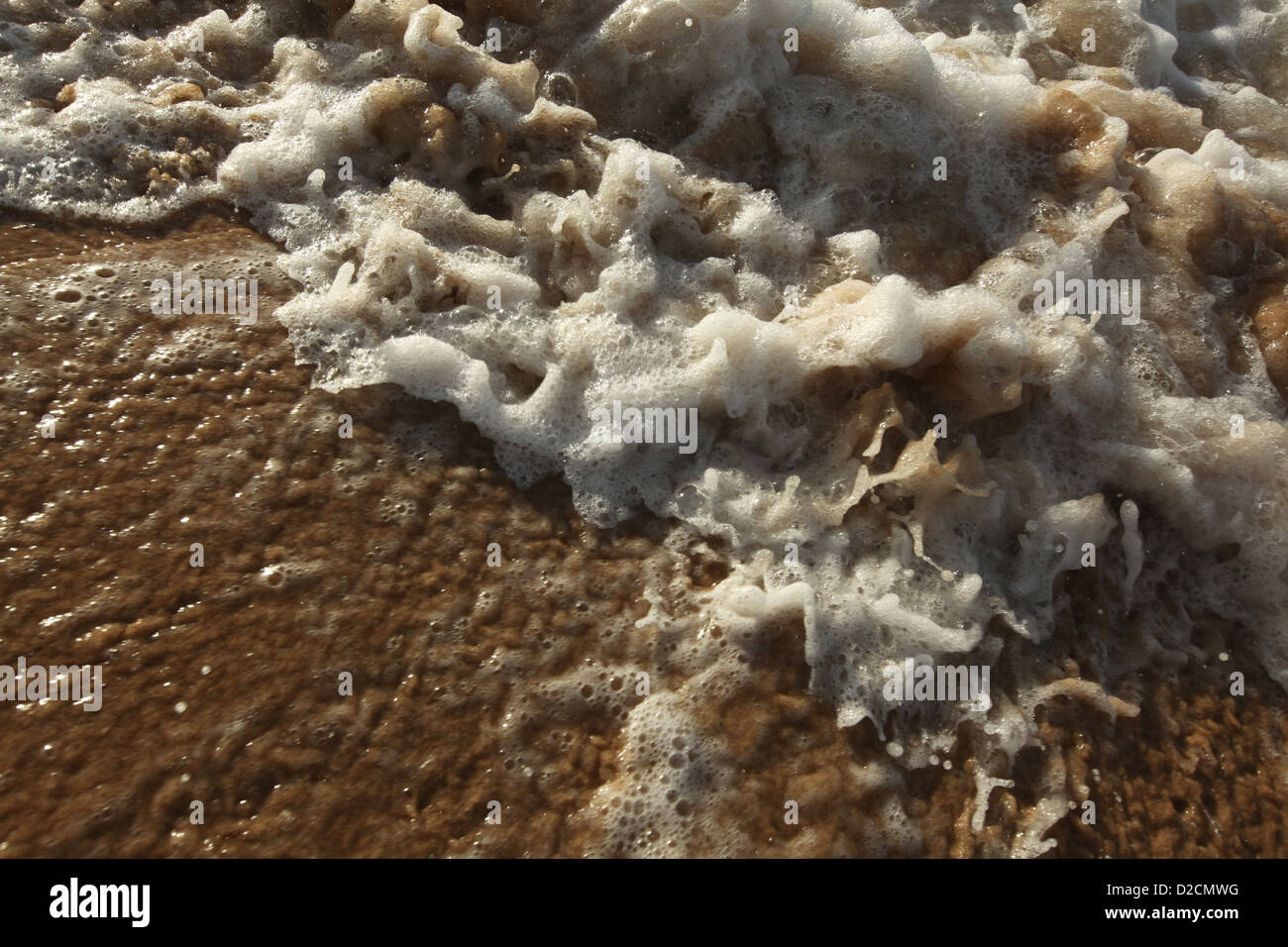 Detail of waves splashing on the edge of a sandy beach Stock Photo - Alamy