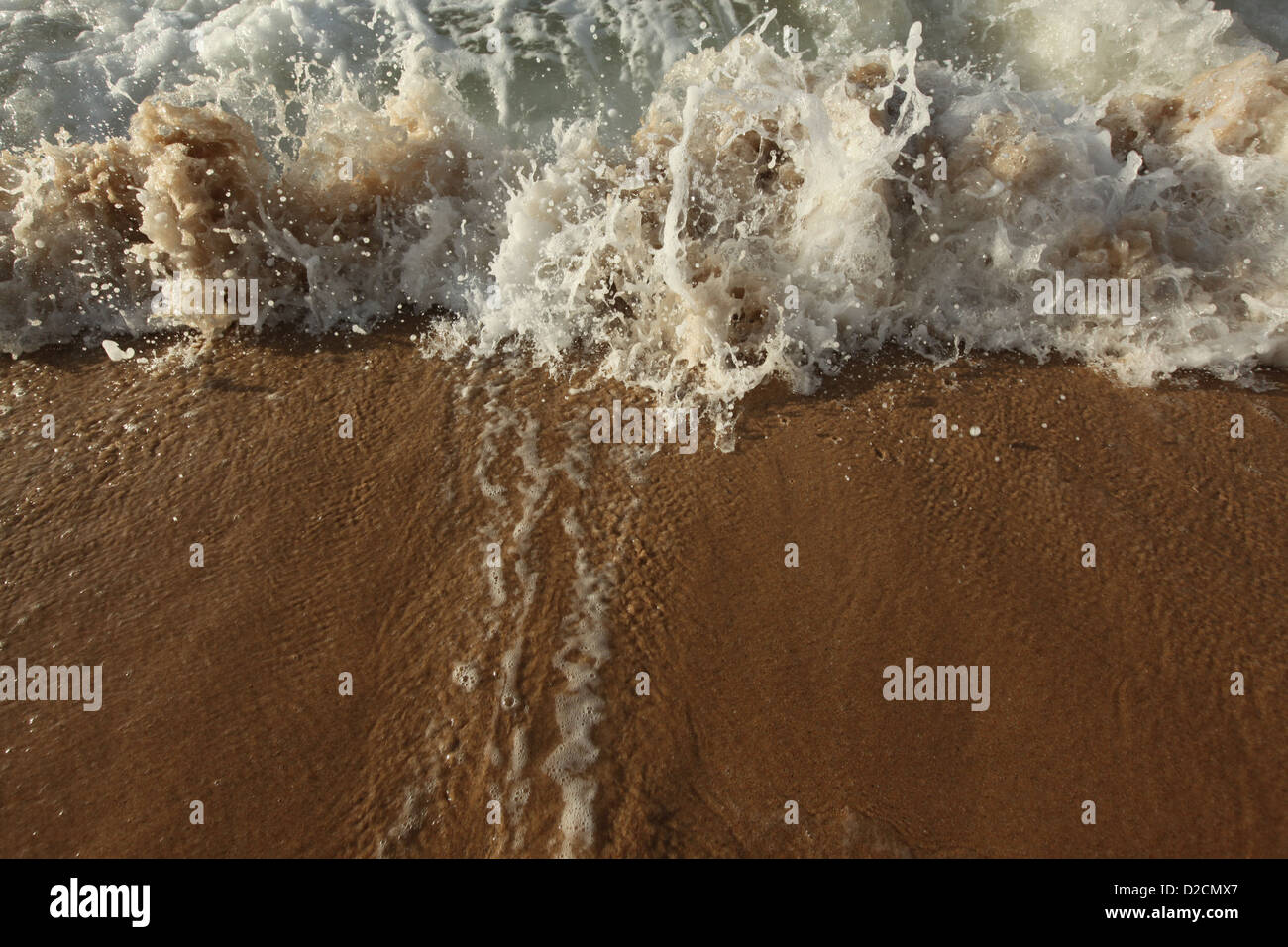 Detail of waves splashing on the edge of a sandy beach Stock Photo - Alamy