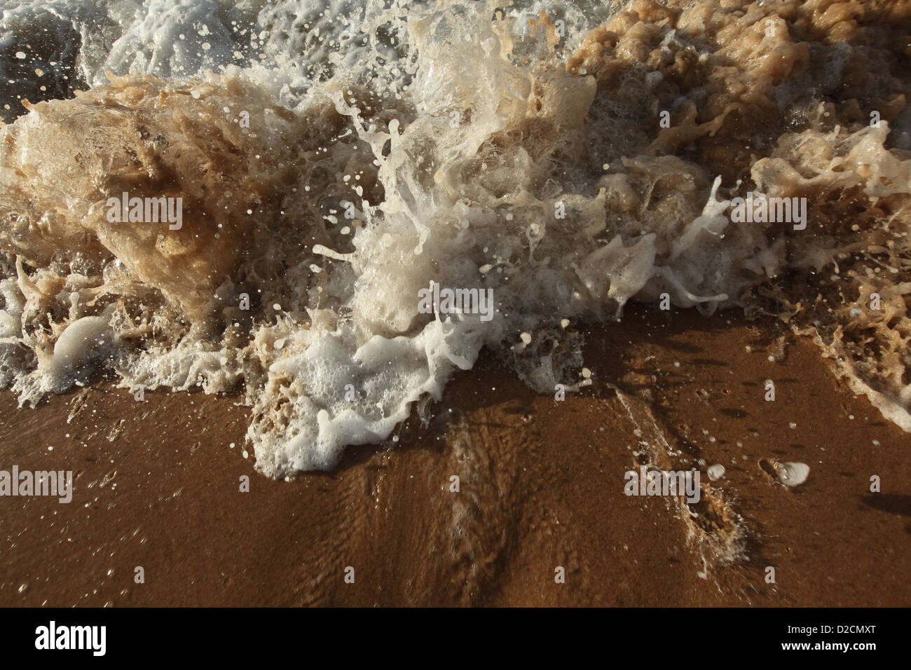 Detail of waves splashing on the edge of a sandy beach Stock Photo - Alamy
