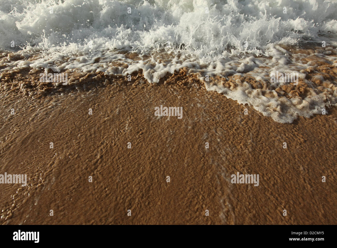 Detail of waves splashing on the edge of a sandy beach Stock Photo - Alamy