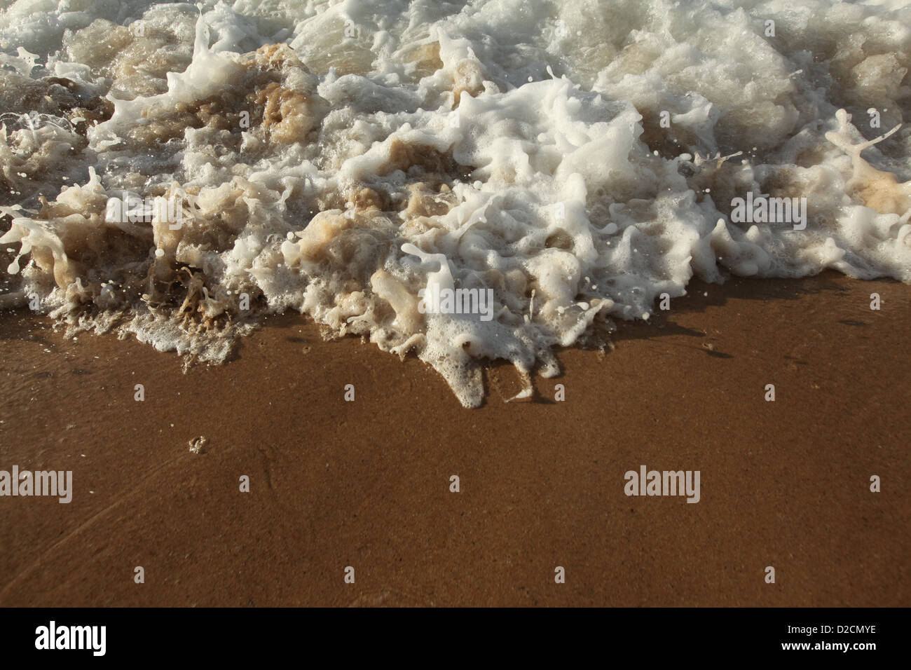 Detail of waves splashing on the edge of a sandy beach Stock Photo - Alamy