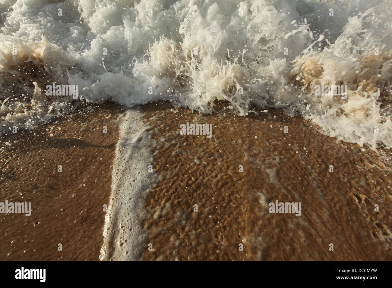 Detail of waves splashing on the edge of a sandy beach Stock Photo - Alamy