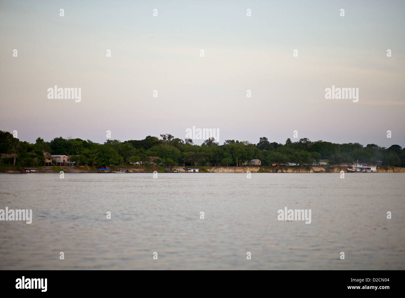Scenic view of a small riverside village along the Amazon River at dusk ...