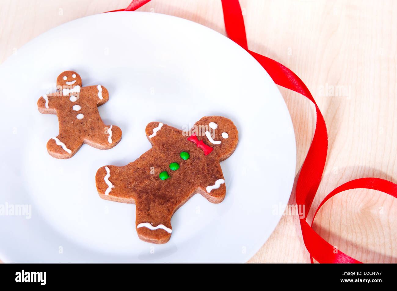 Two gingerbread men isolated on a plate and red ribbon - Christmas time ...