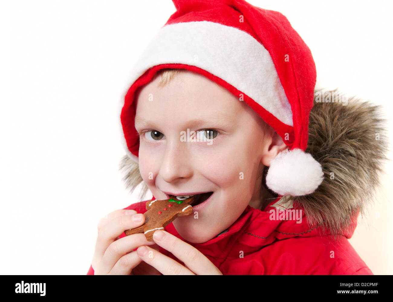 Young boy wearing santa hat eating gingerbread man Stock Photo - Alamy