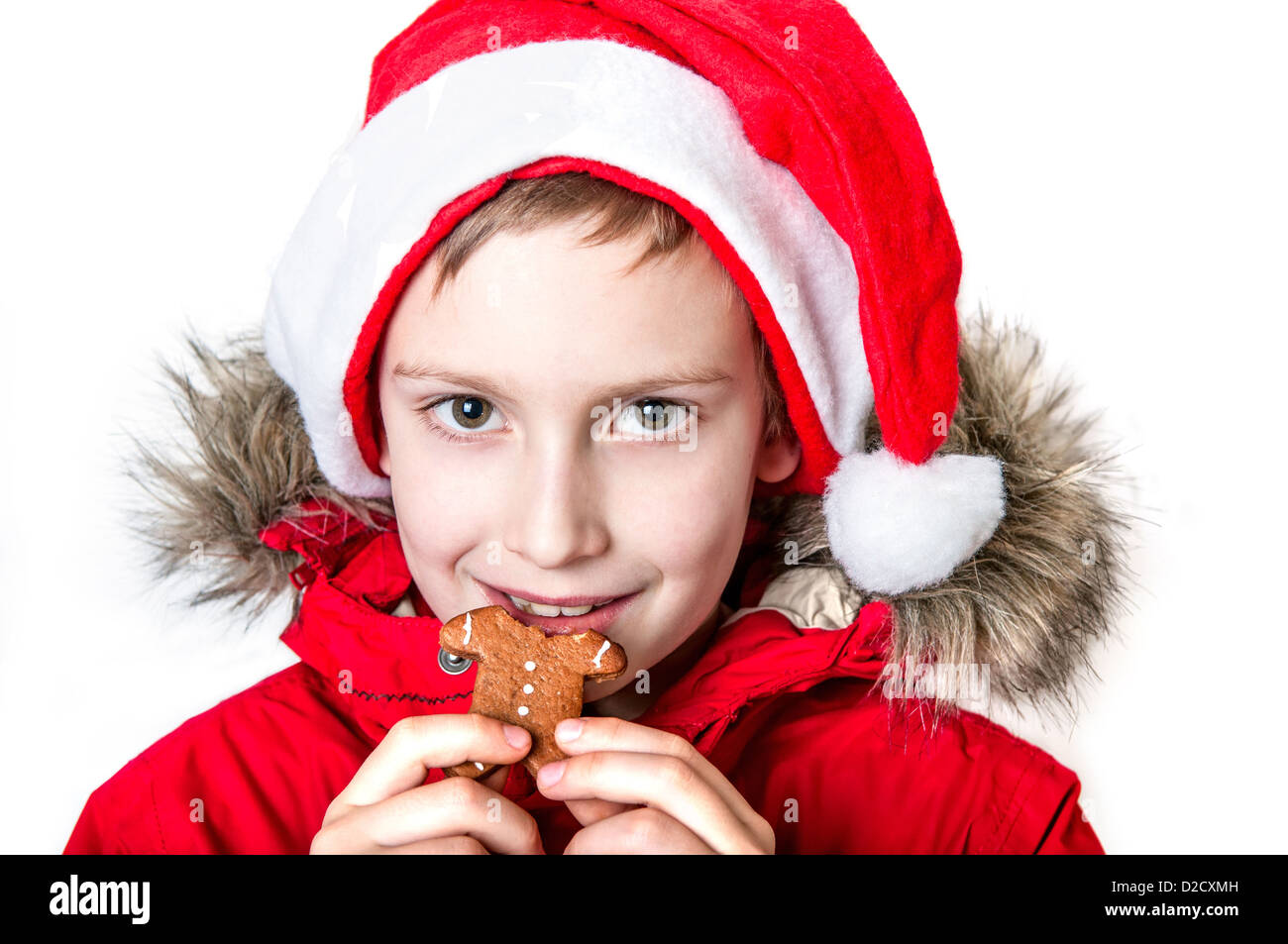 Smiling boy wearing santa hat eating gingerbread man Stock Photo - Alamy