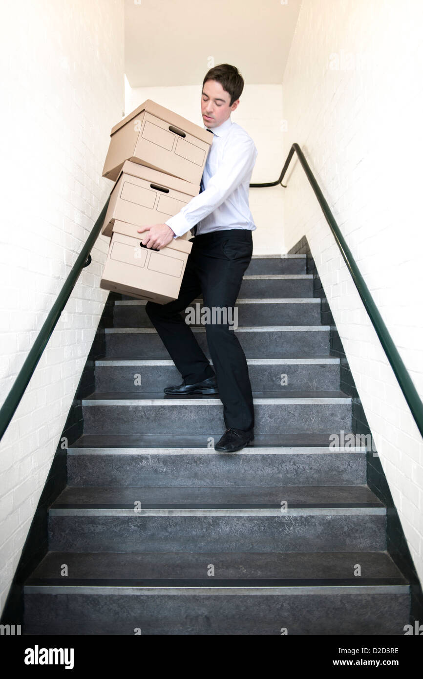 MODEL RELEASED Carrying boxes Office worker carrying boxes down stairs ...