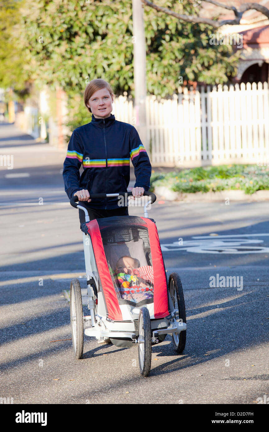 A woman walking on a street and pushing a baby stroller Stock Photo - Alamy