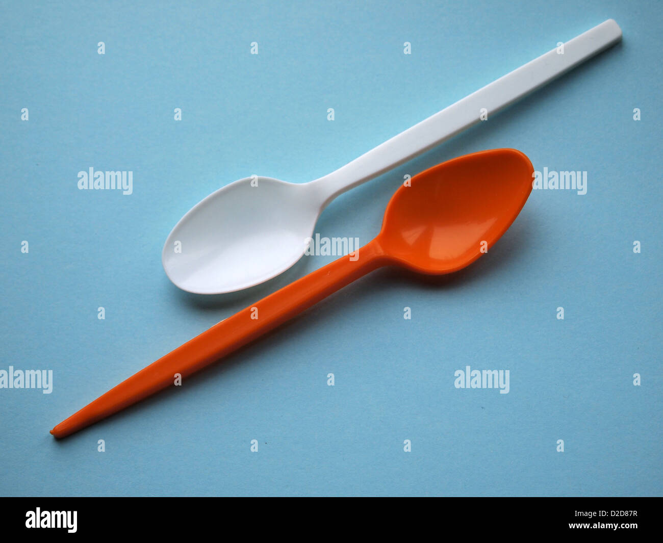 orange and white pastic spoons on blue background Stock Photo - Alamy