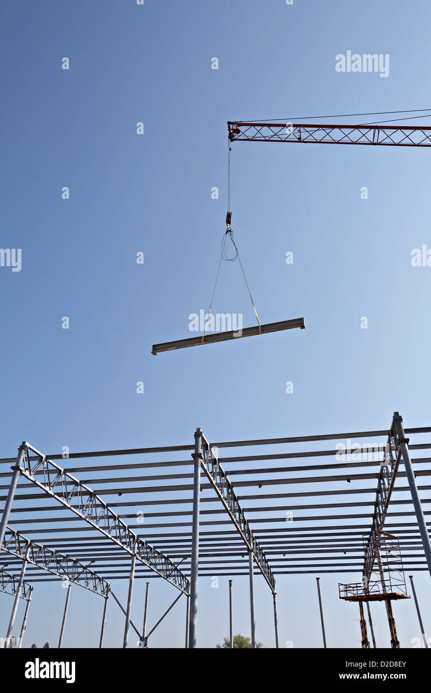 Crane lowering steel beam towards construction frame Stock Photo - Alamy