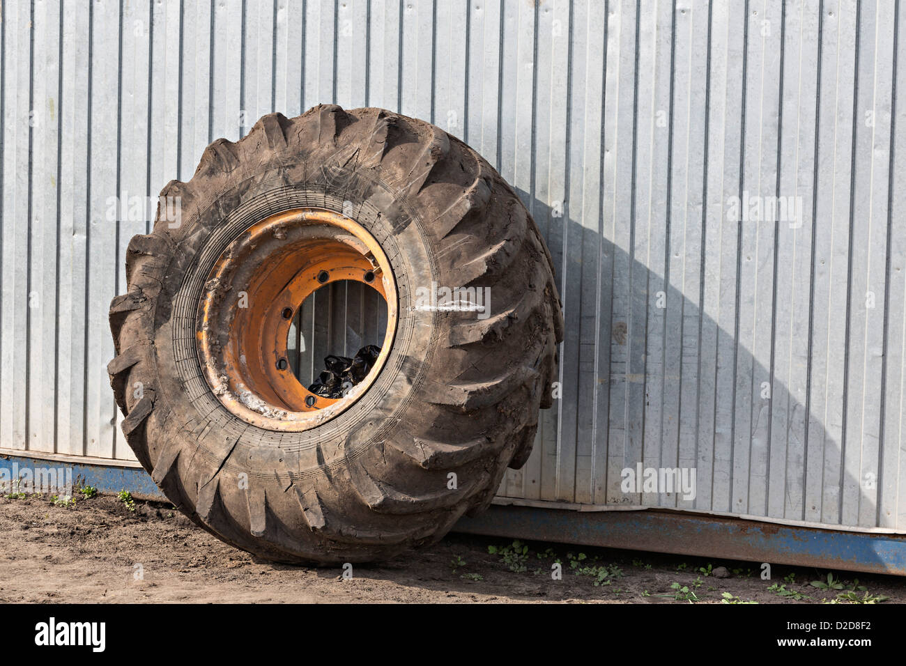 Construction vehicle wheel leaning against industrial building Stock ...