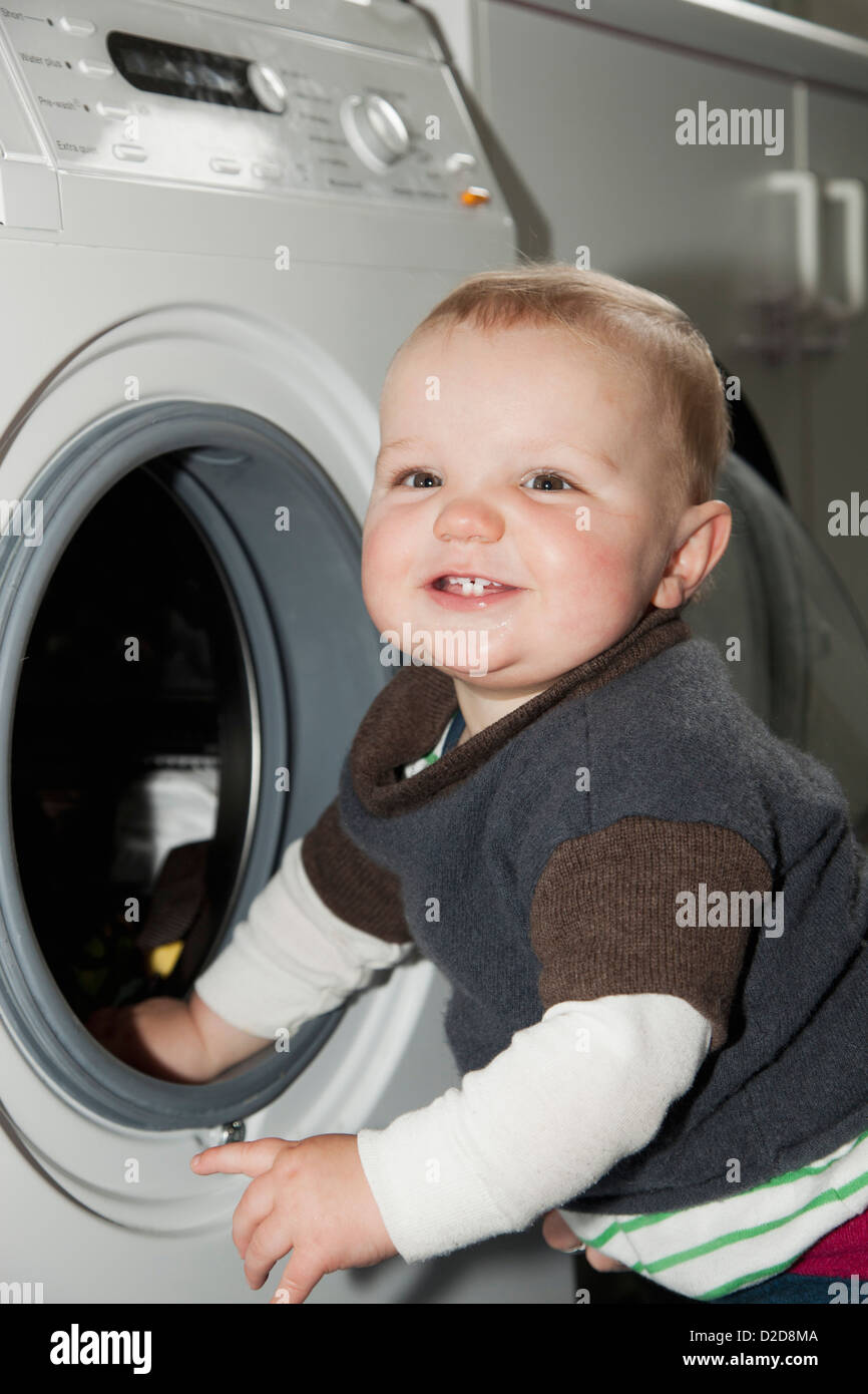 A baby boy standing next to a washing machine Stock Photo - Alamy