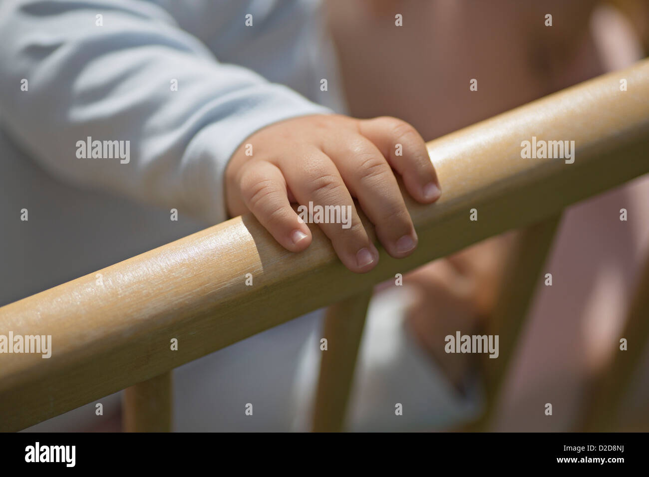 Baby's hand on crib railing Stock Photo - Alamy