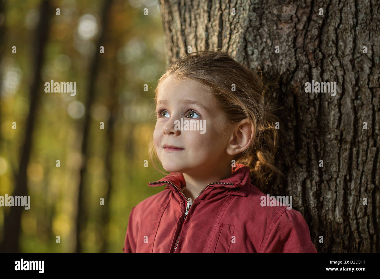 A young girl leaning against a tree trunk Stock Photo - Alamy