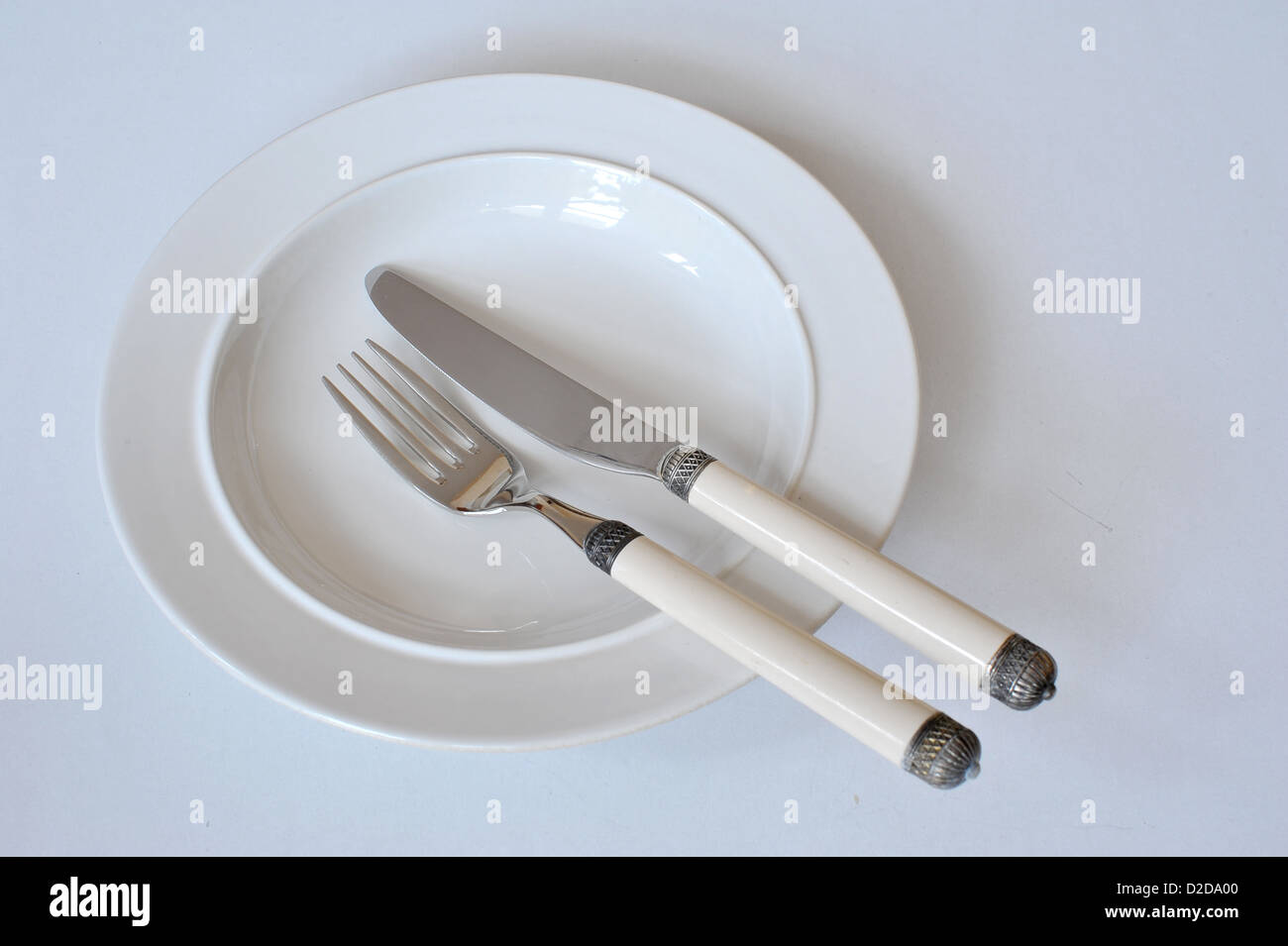steel kitchen knife and prong on plate Stock Photo - Alamy
