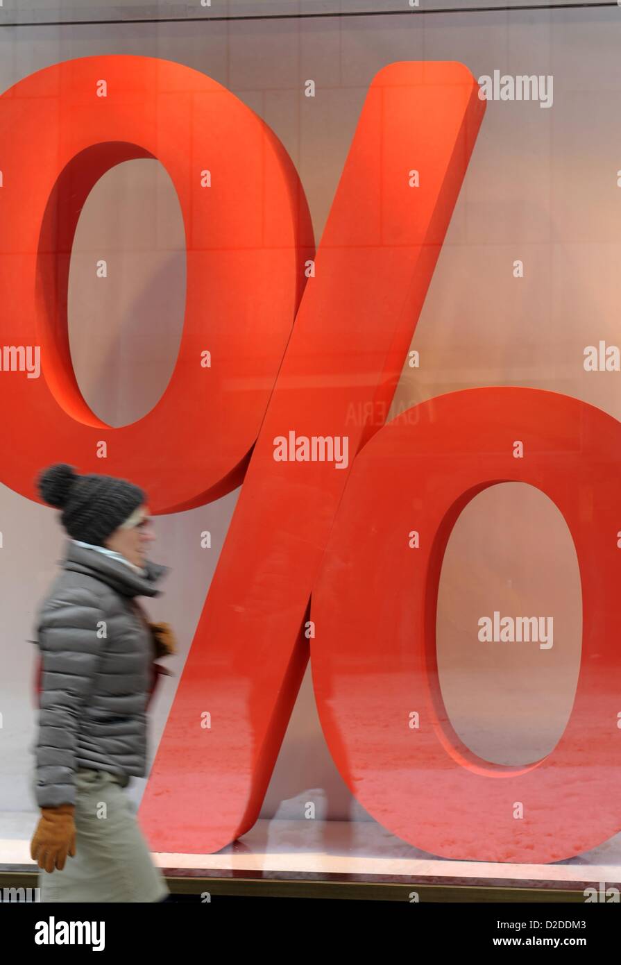 A woman walks by shop windows with a percent sign, in Munich, Germany ...