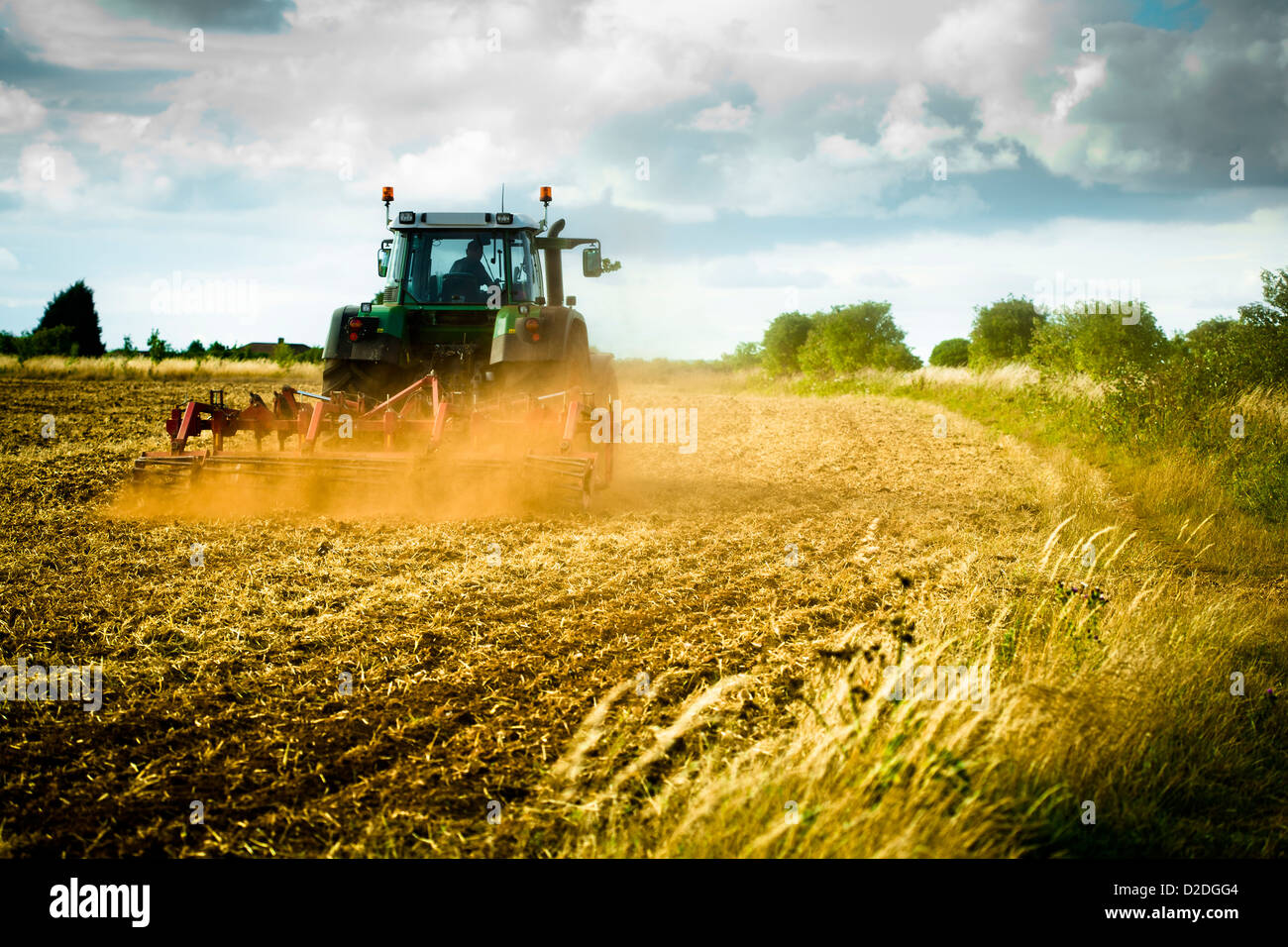 Tractor ploughing a field with a trail of dust behind it Stock Photo ...