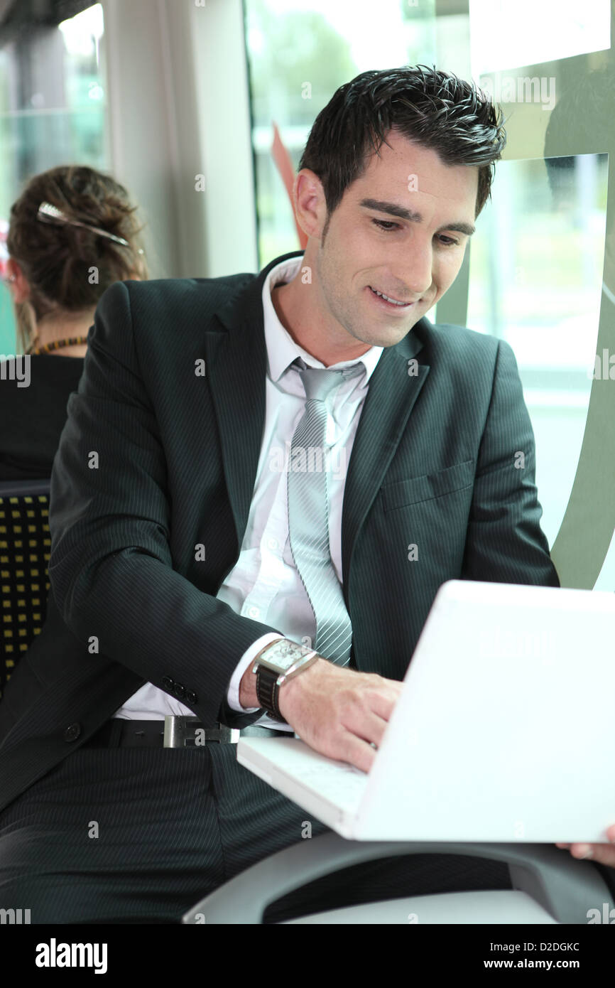 Young professional riding the tram typing on laptop computer Stock ...