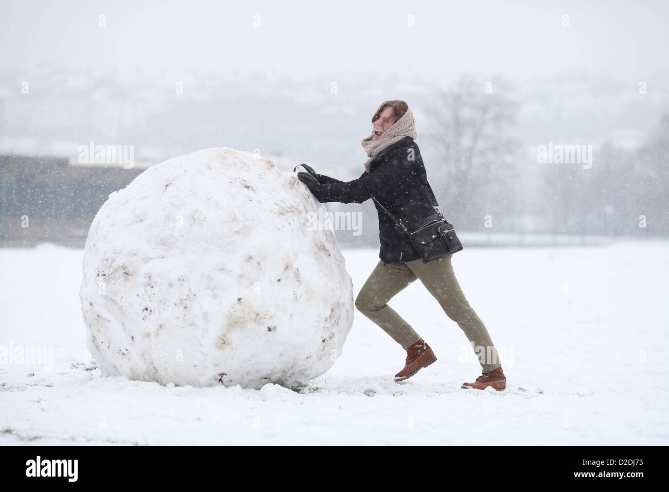 Woman tries to push a massive snowball after heavy snowfall on the ...