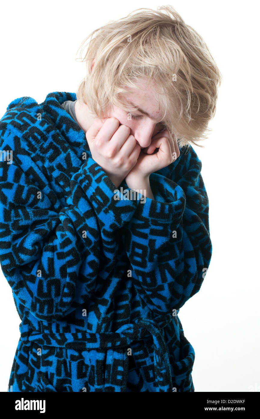 Upset and distressed blond-haired teenage boy in his dressing gown ...