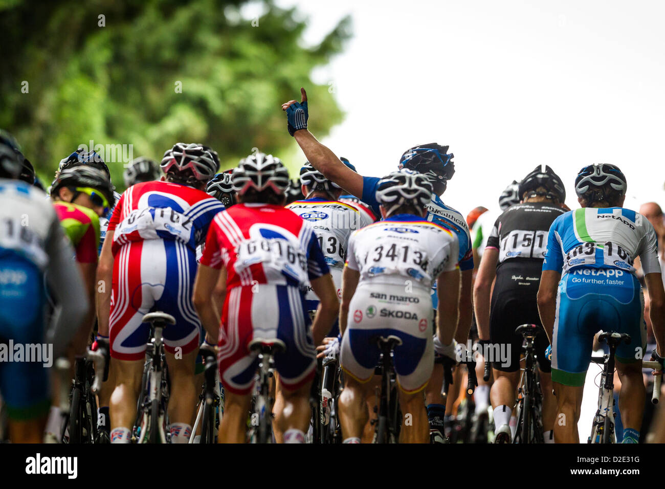 A rider raises his arm above the melee of the peloton to signal his ...