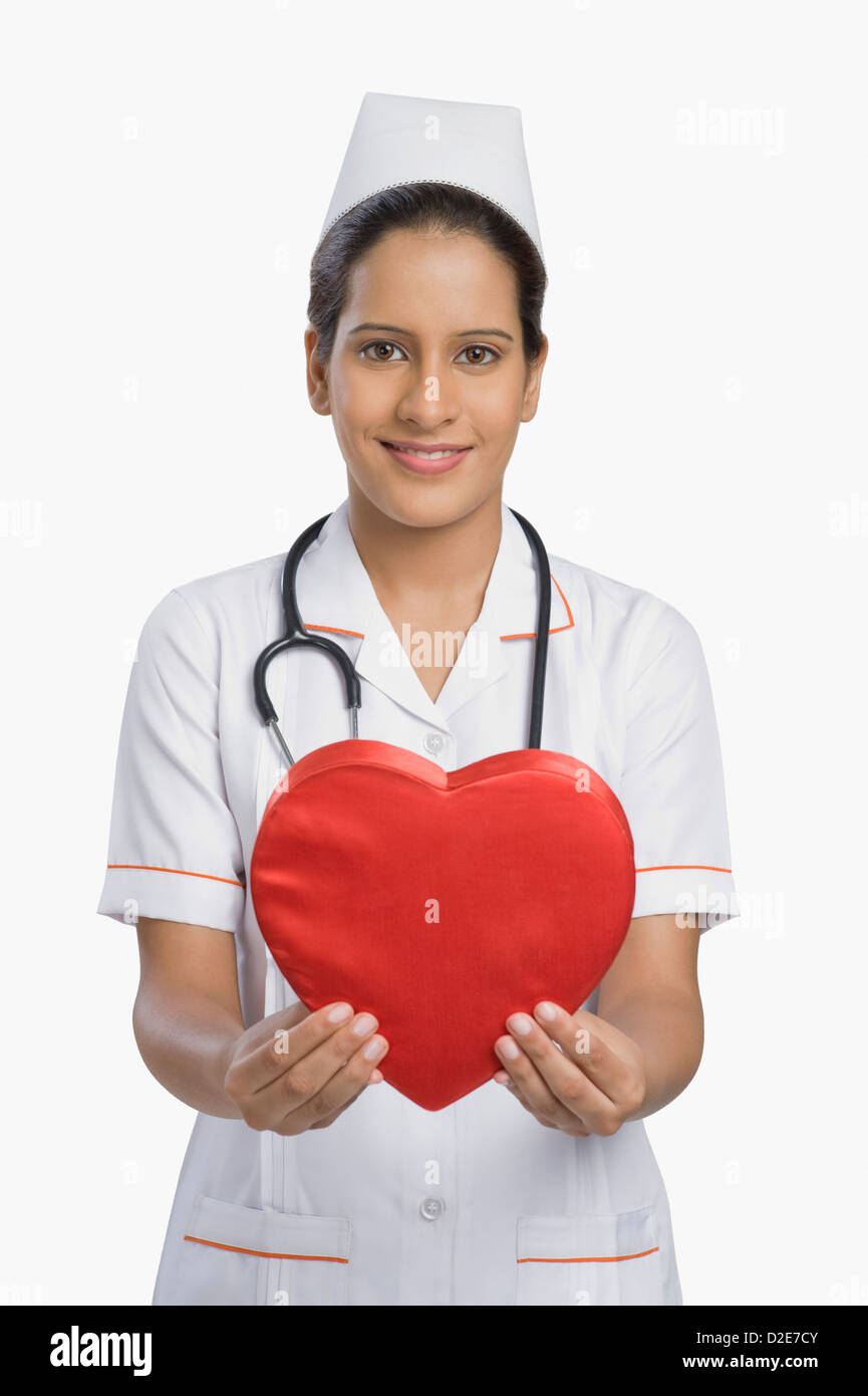 Female nurse holding a heart shape and smiling Stock Photo - Alamy