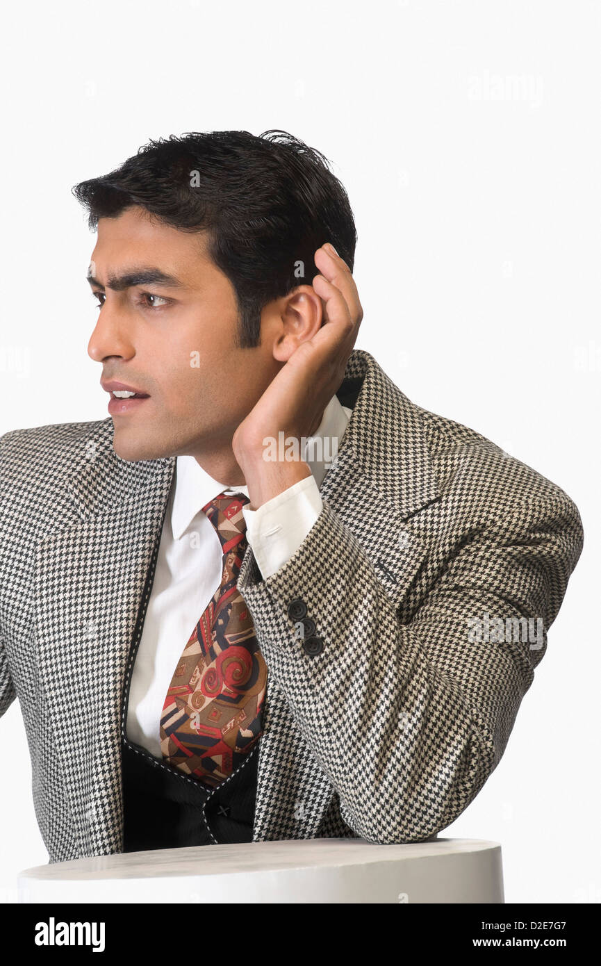 Businessman cupping his ears Stock Photo - Alamy