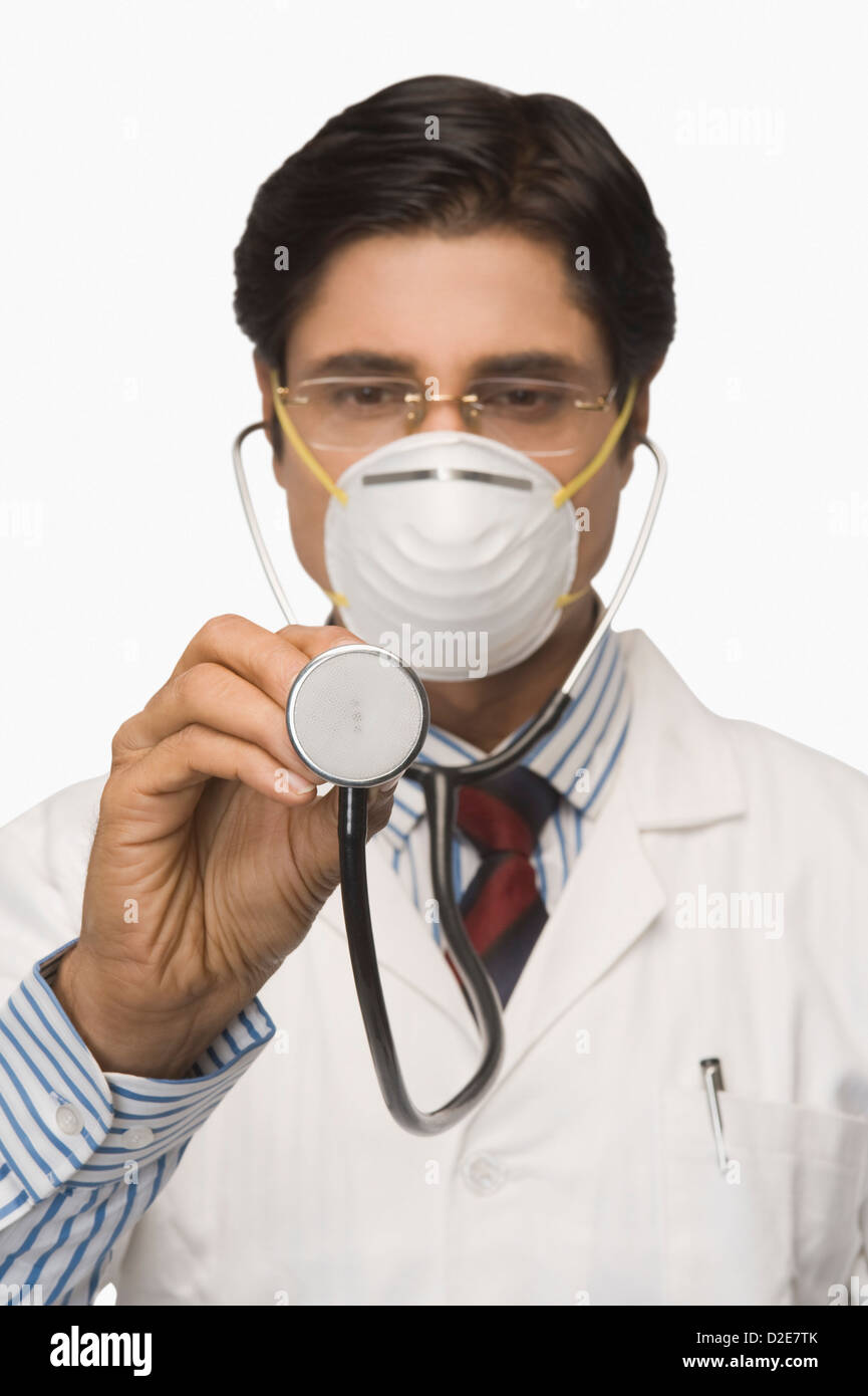 Doctor wearing a flu mask and pretending to listen heartbeat with a ...