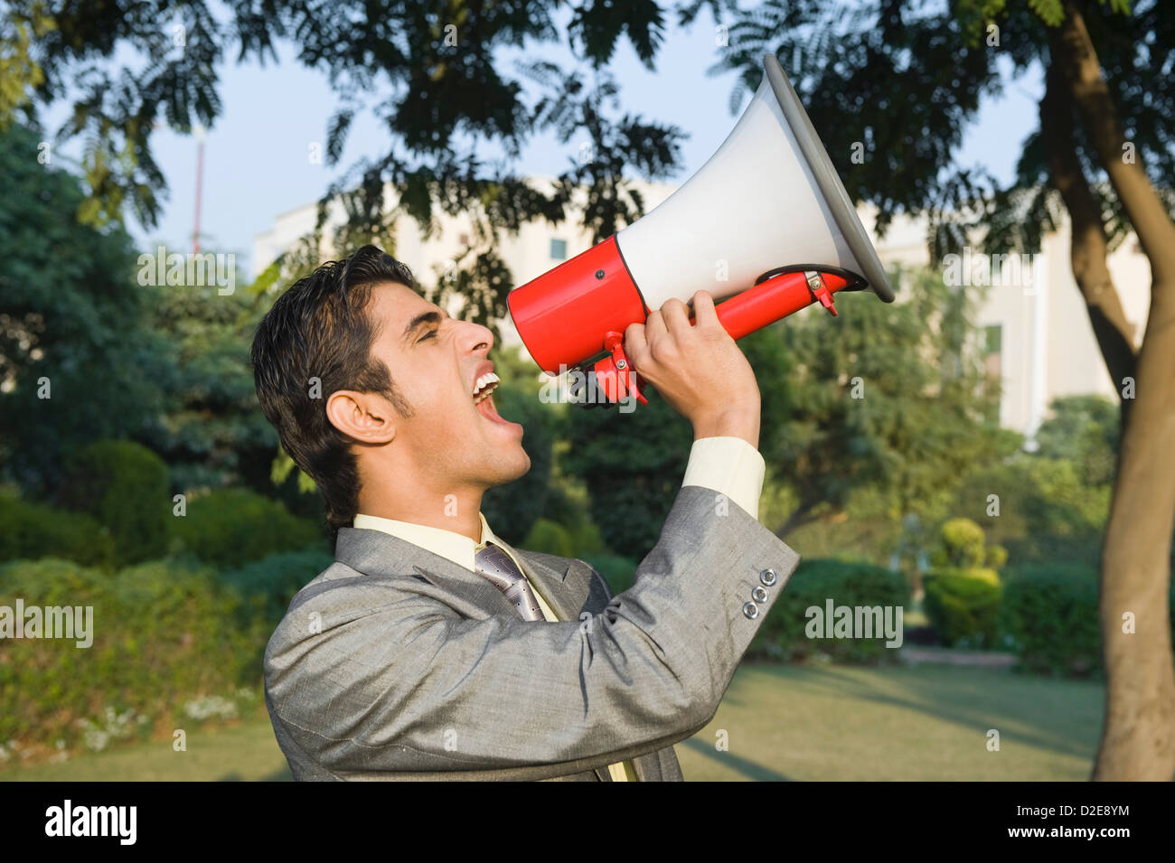 Businessman shouting into a megaphone in a park Stock Photo - Alamy
