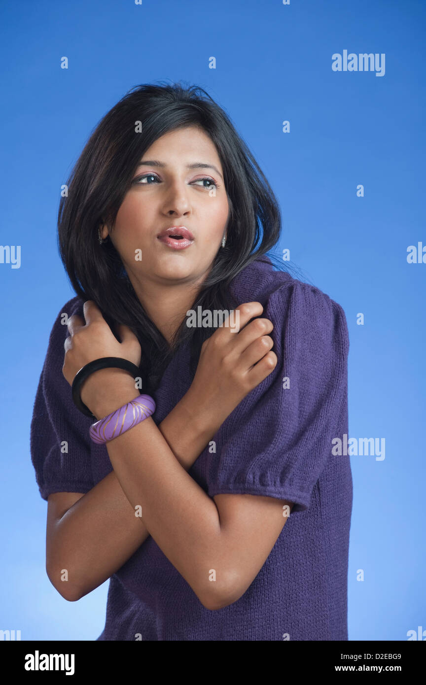 Woman shivering against blue background Stock Photo - Alamy