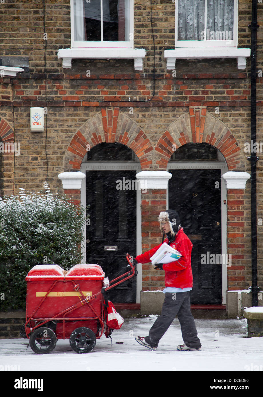 Postman walking along pavement delivering post in Snow in London - UK ...
