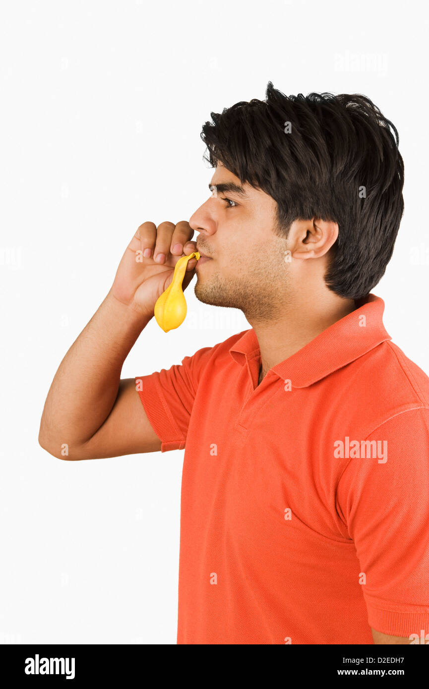 Young man blowing up balloon hi-res stock photography and images - Alamy
