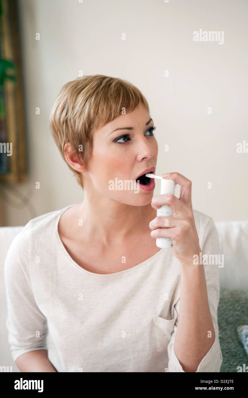 WOMAN USING SPRAY IN MOUTH Stock Photo - Alamy
