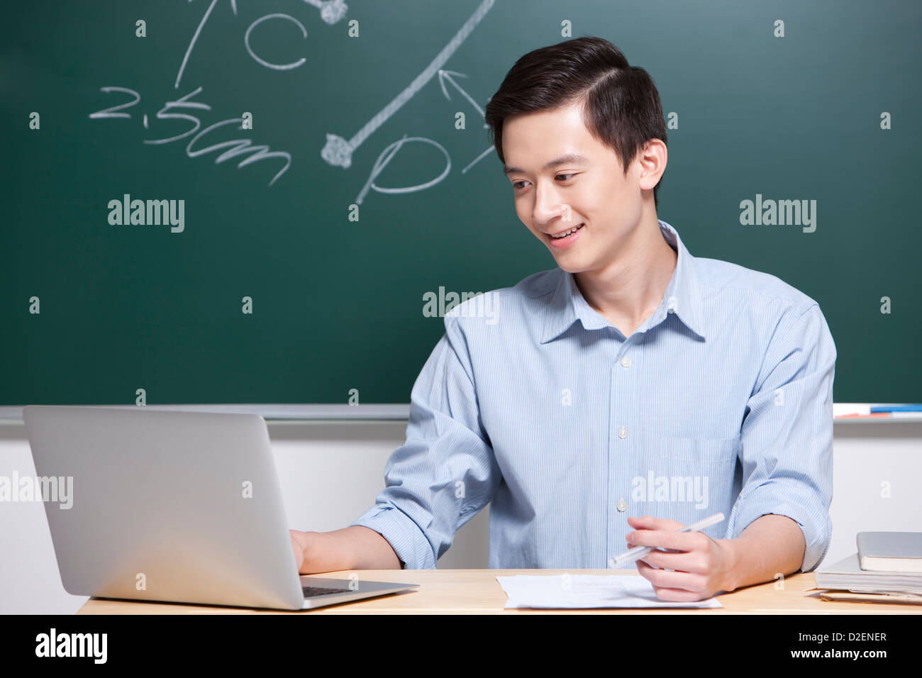 Cheerful male teacher using laptop in classroom Stock Photo - Alamy