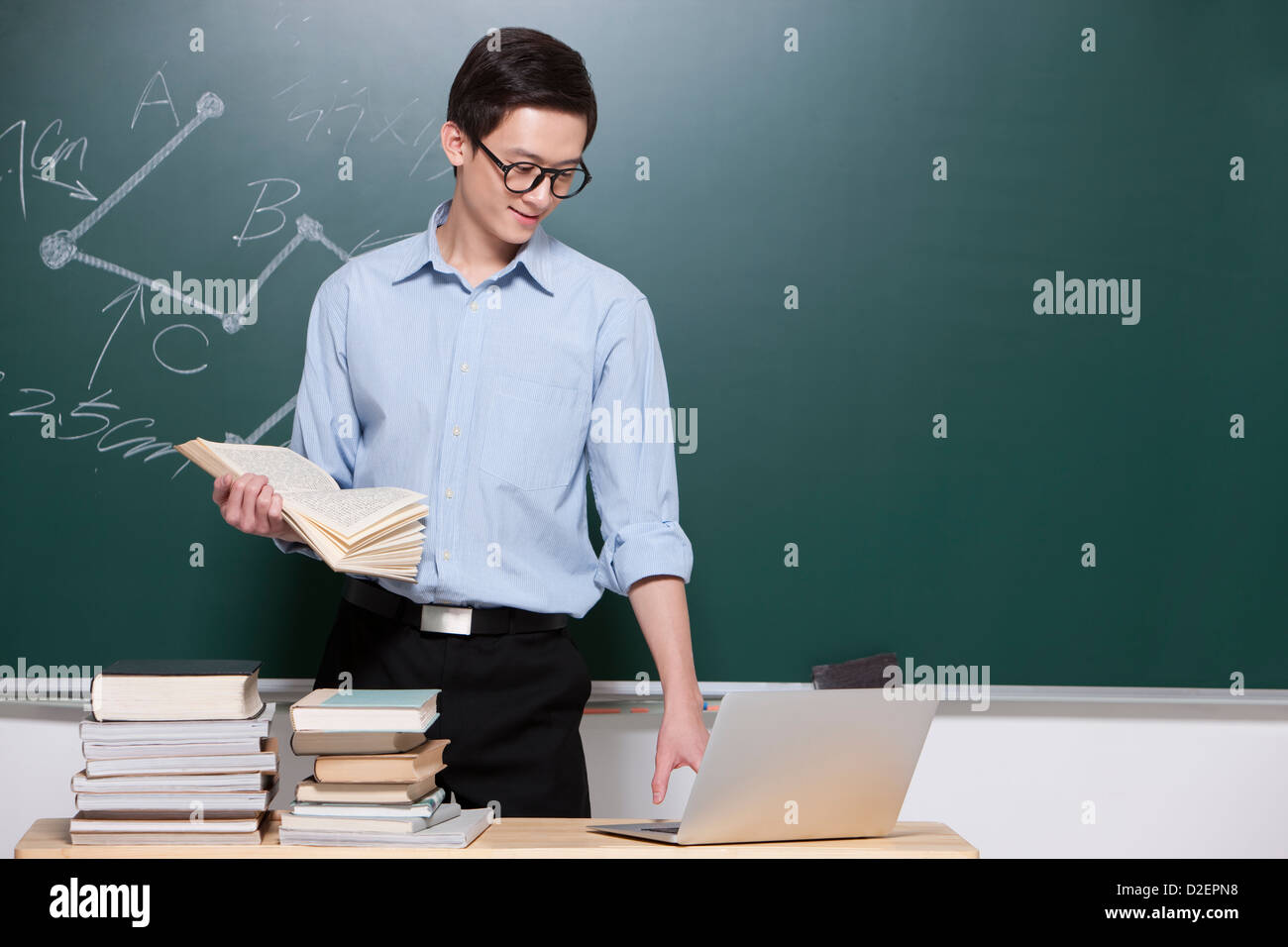 Professional male teacher using laptop in classroom Stock Photo - Alamy