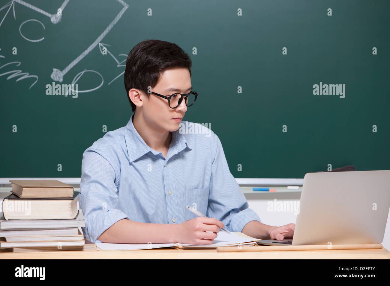 Professional male teacher using laptop in classroom Stock Photo - Alamy