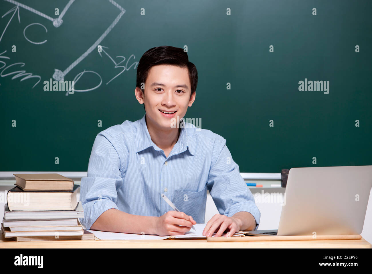 Cheerful male teacher reviewing homework in classroom Stock Photo - Alamy
