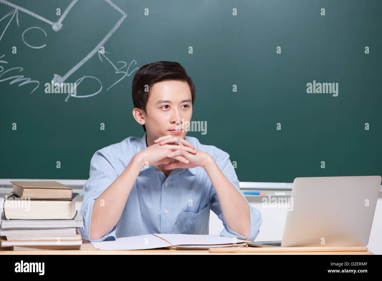 Serious male teacher hand on chin in classroom Stock Photo - Alamy