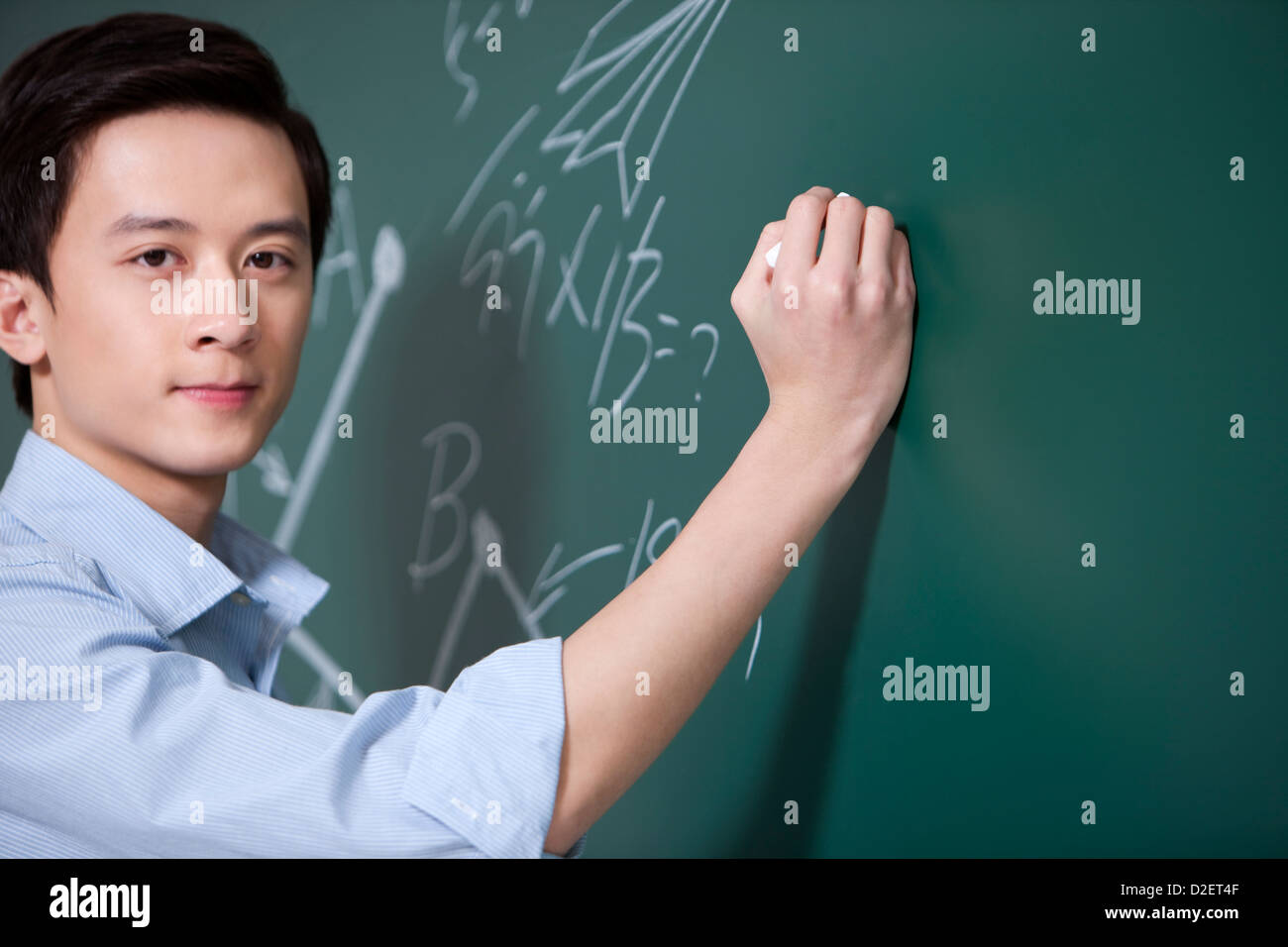 Professional male teacher writing on blackboard Stock Photo - Alamy