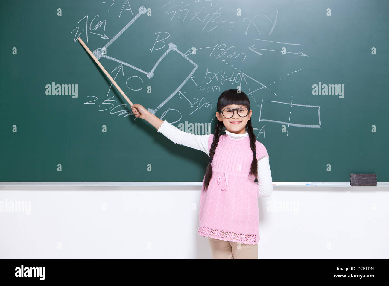Humorous little girl playing teacher in classroom Stock Photo - Alamy
