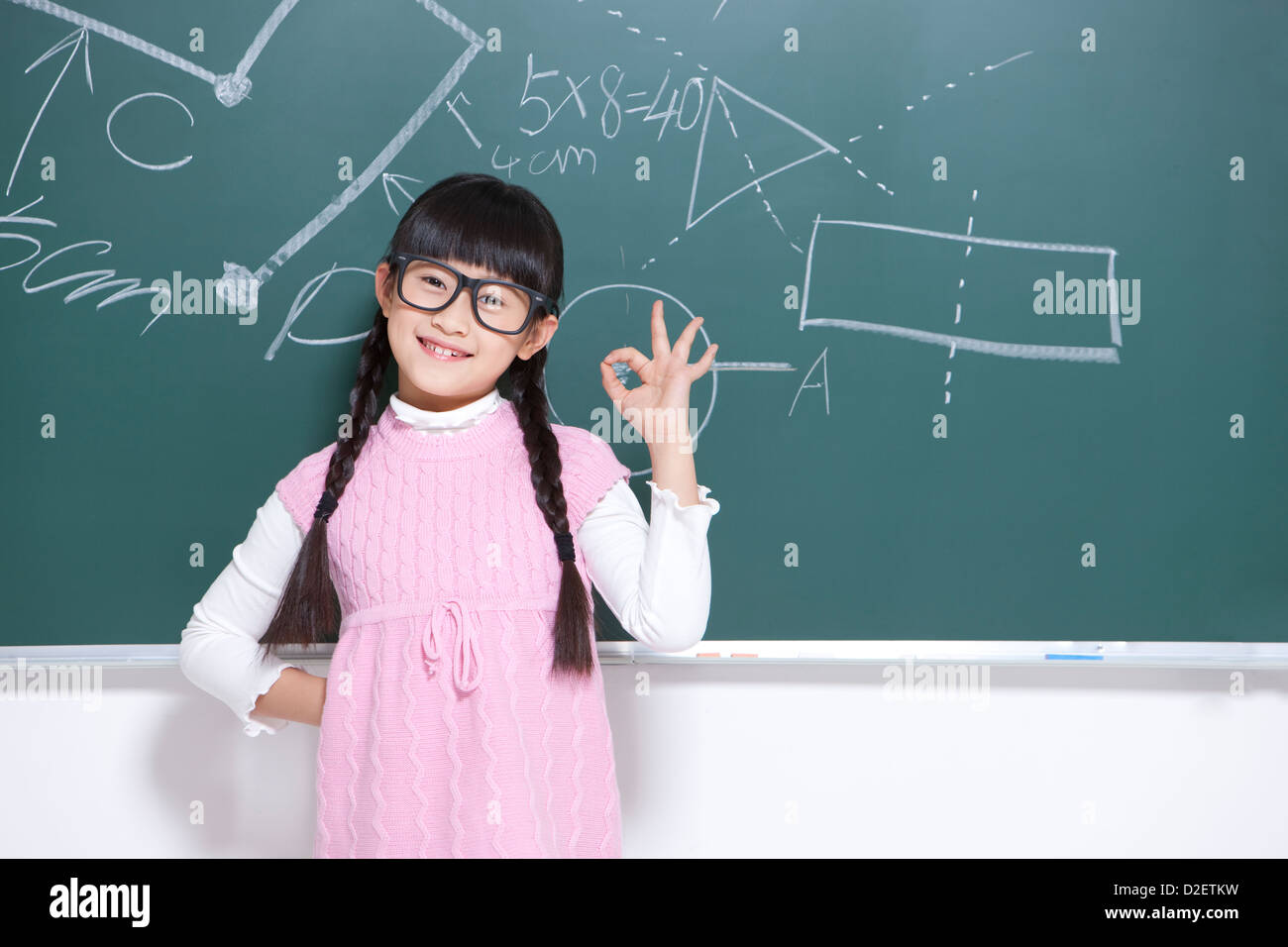 Cheerful little girl doing hand sign in classroom Stock Photo - Alamy