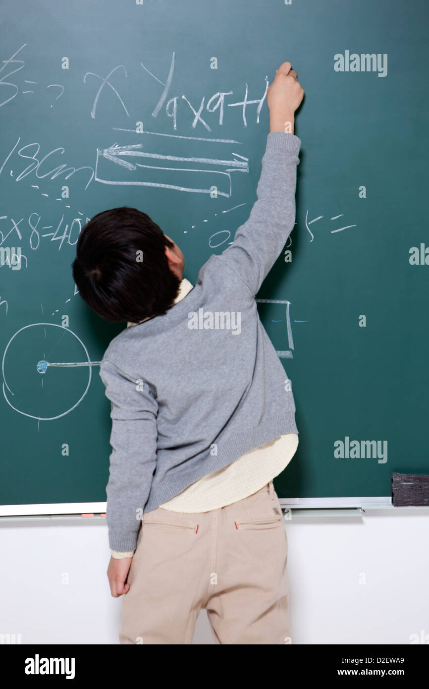 Happy little boy writing on blackboard Stock Photo - Alamy