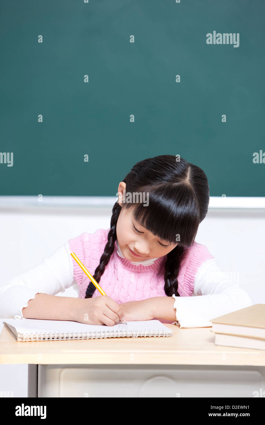 Lovely schoolgirl writing in classroom Stock Photo - Alamy