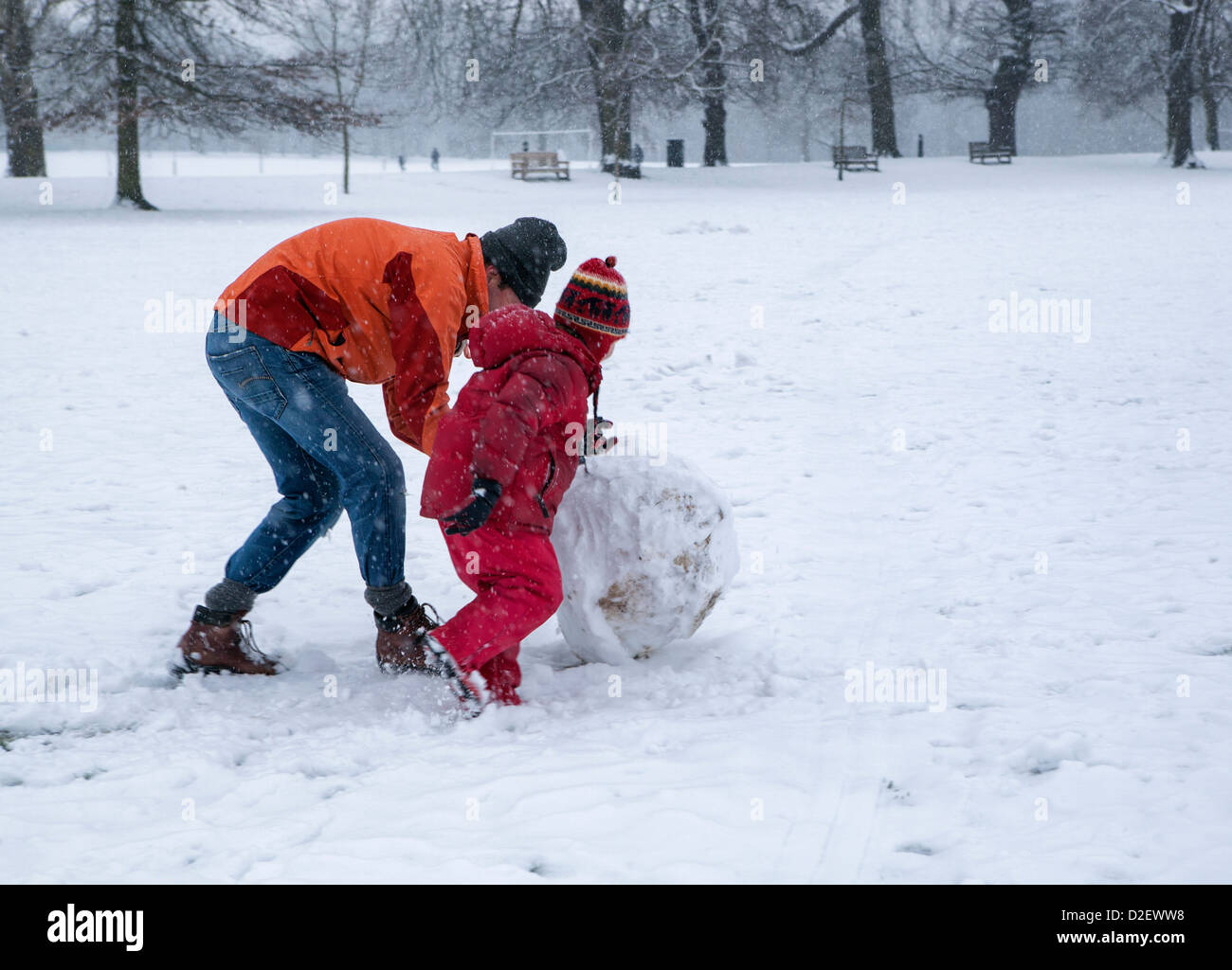 A man and his young son rolling a snowball in the park of Marble Hill ...