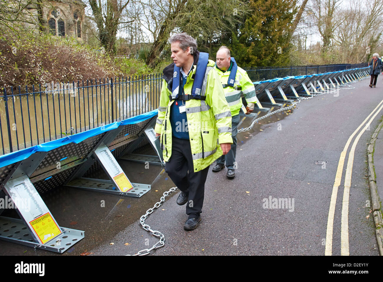 Environment agency workers, wearing life jackets, inspect a temporary ...