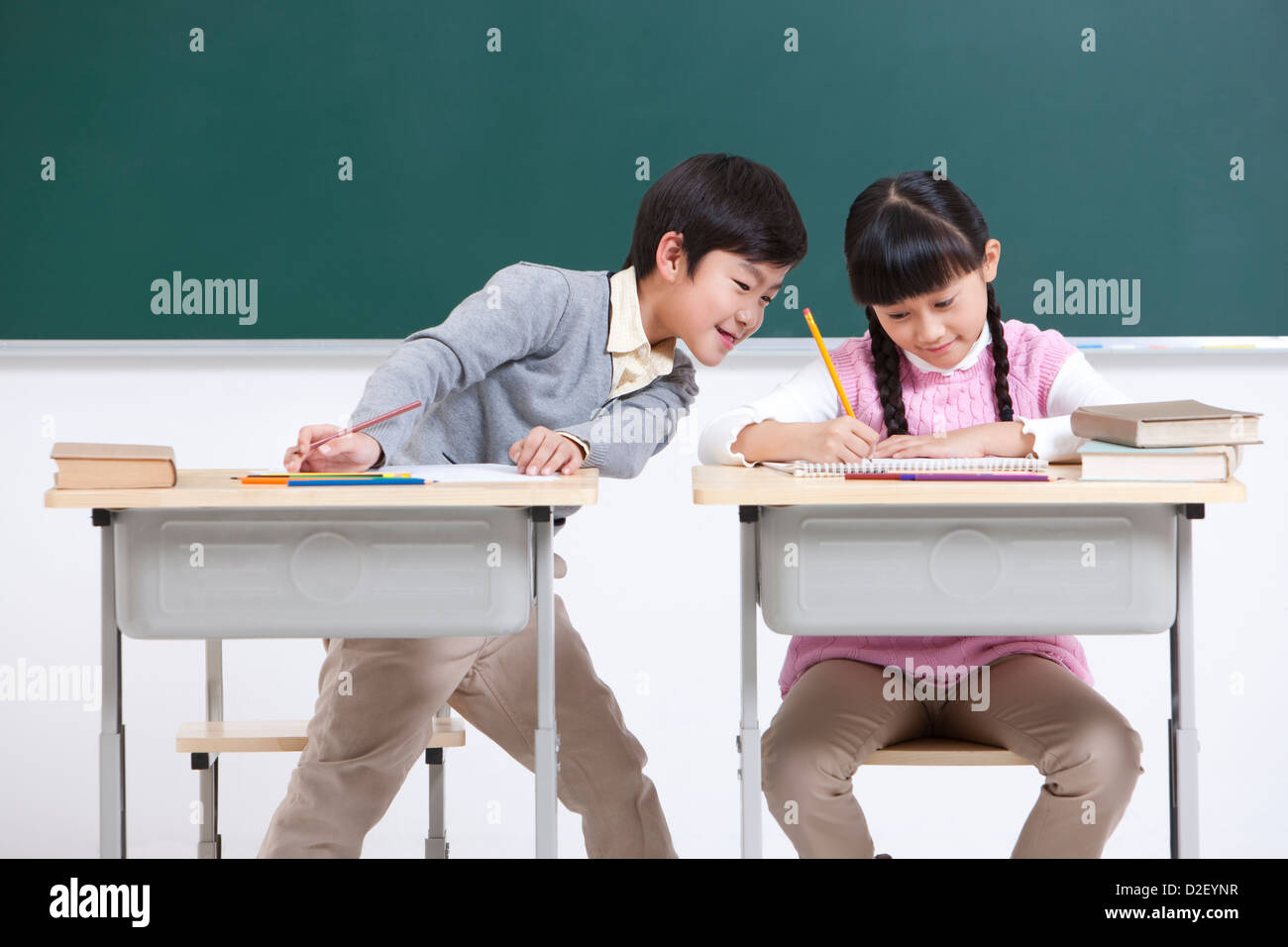 Happy schoolchildren doing homework in classroom Stock Photo - Alamy