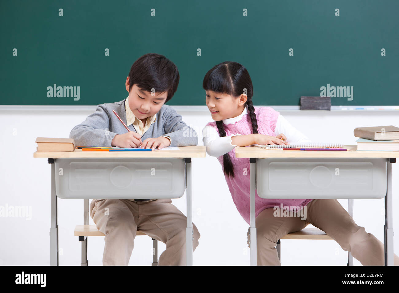 Happy schoolchildren doing homework in classroom Stock Photo - Alamy
