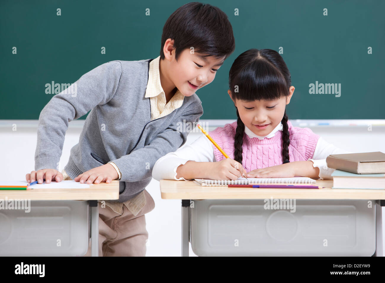 Happy schoolchildren doing homework in classroom Stock Photo - Alamy