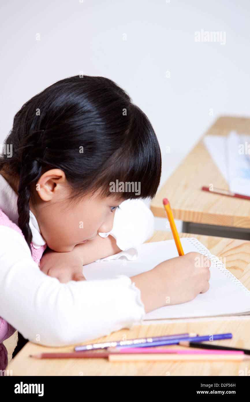 Lovely schoolgirl writing in classroom Stock Photo - Alamy