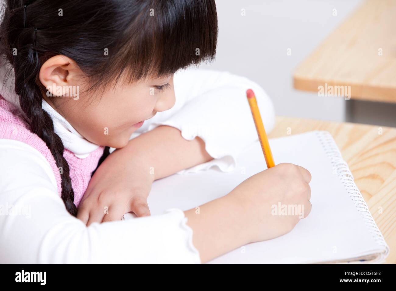 Lovely schoolgirl writing in classroom Stock Photo - Alamy